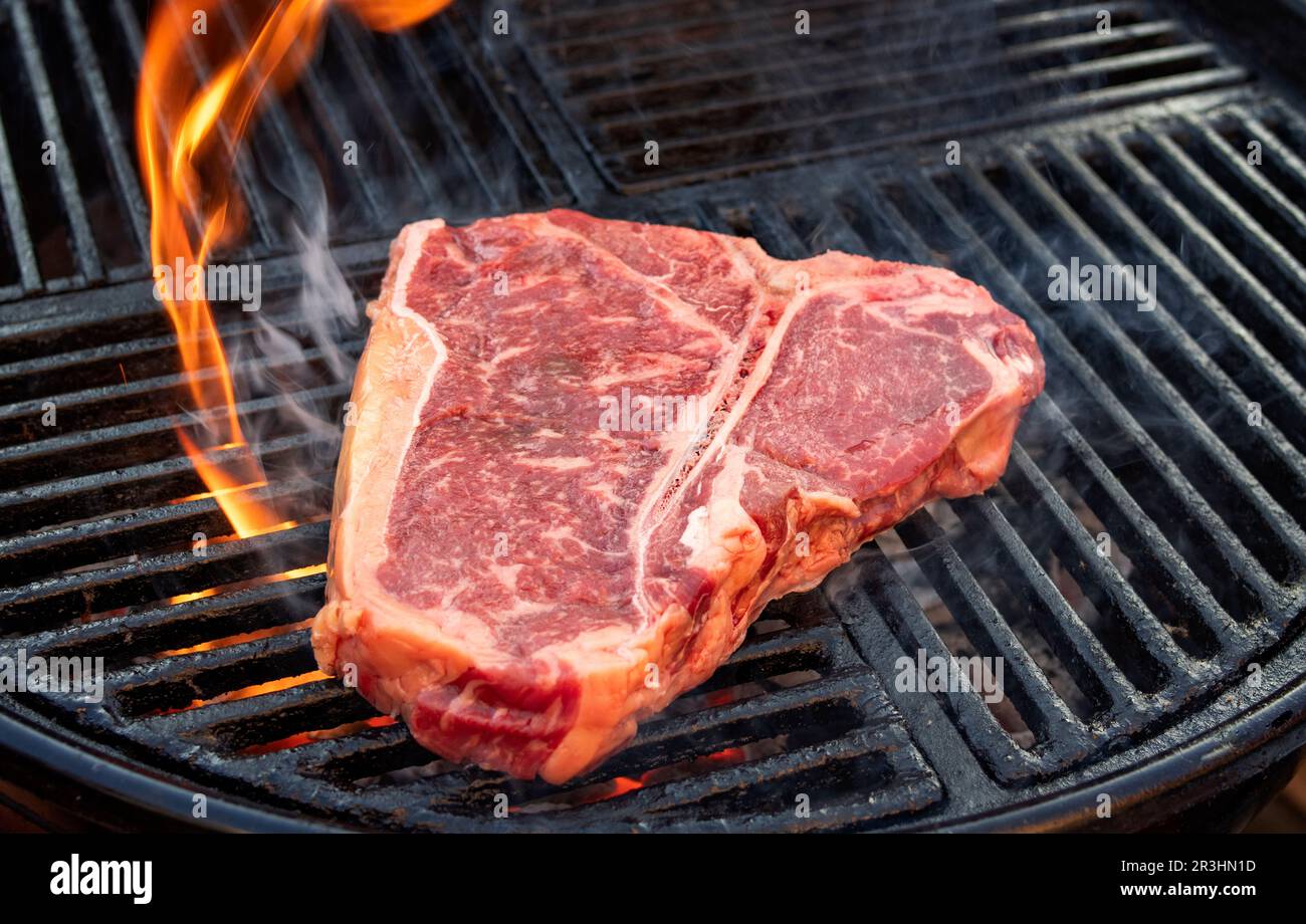 Raw dry aged wagyu porterhouse beef steak grilled as close-up on a ...