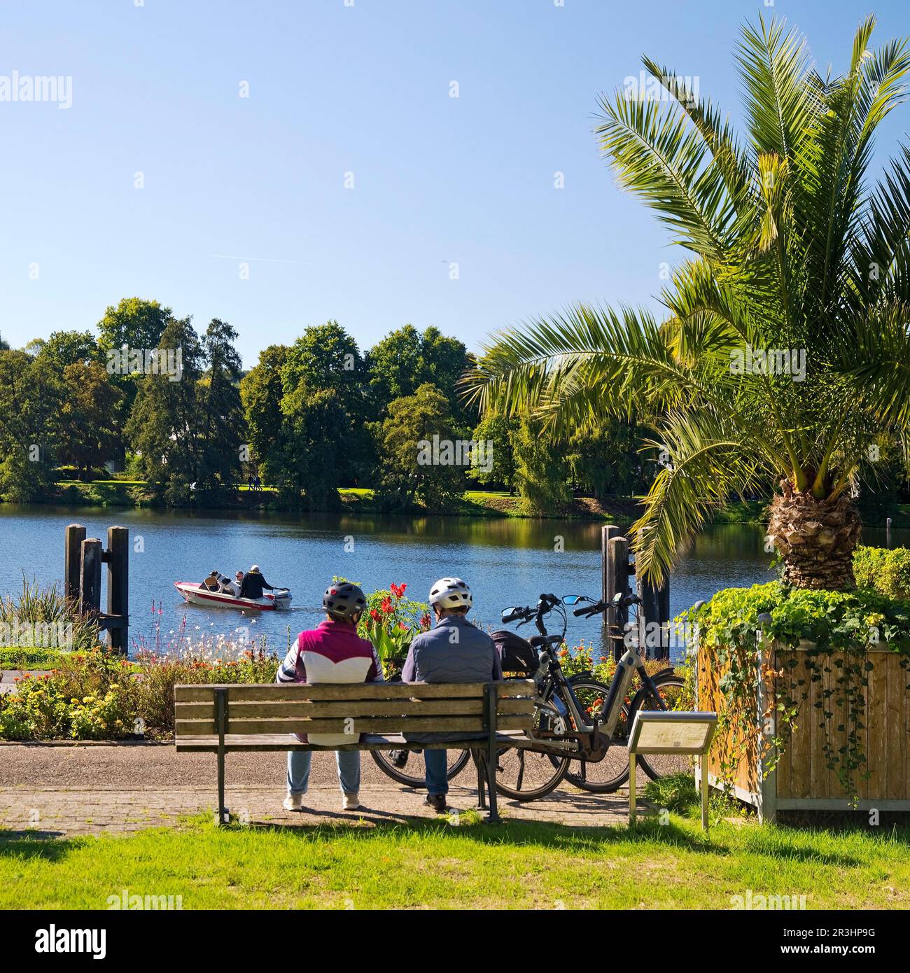 Cyclists on the Ruhr Valley Cycle Path with palm trees, reservoir ...