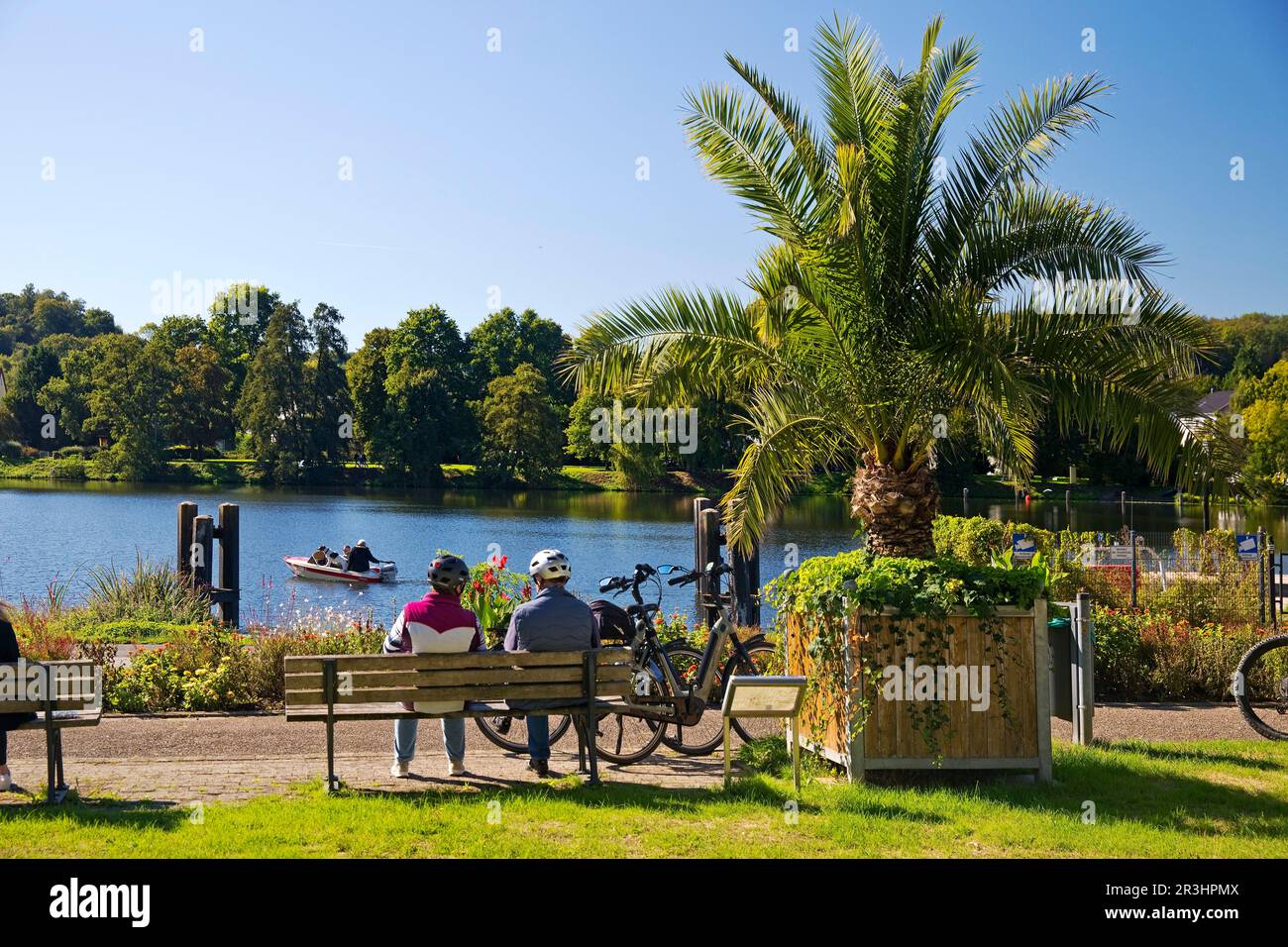 Cyclists on the Ruhr Valley Cycle Path with palm trees, reservoir ...