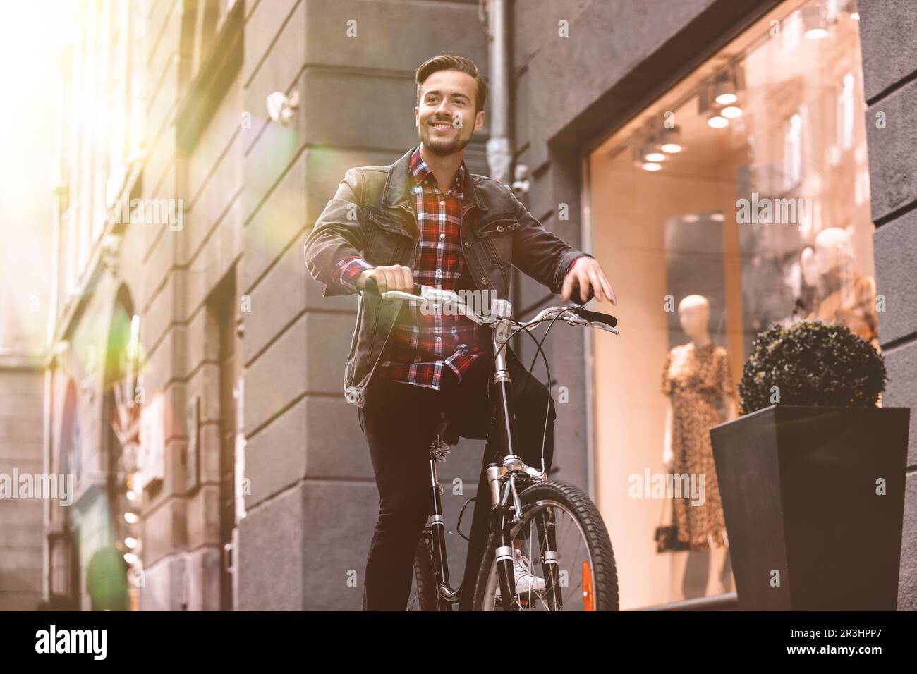 Handsome happy man riding bicycle in city on sunny day, low angle view ...