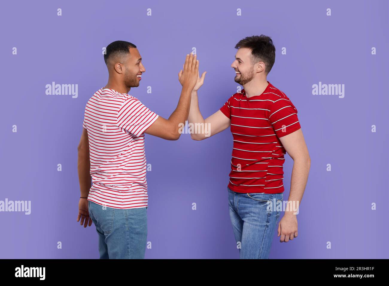 Men giving high five on purple background Stock Photo - Alamy