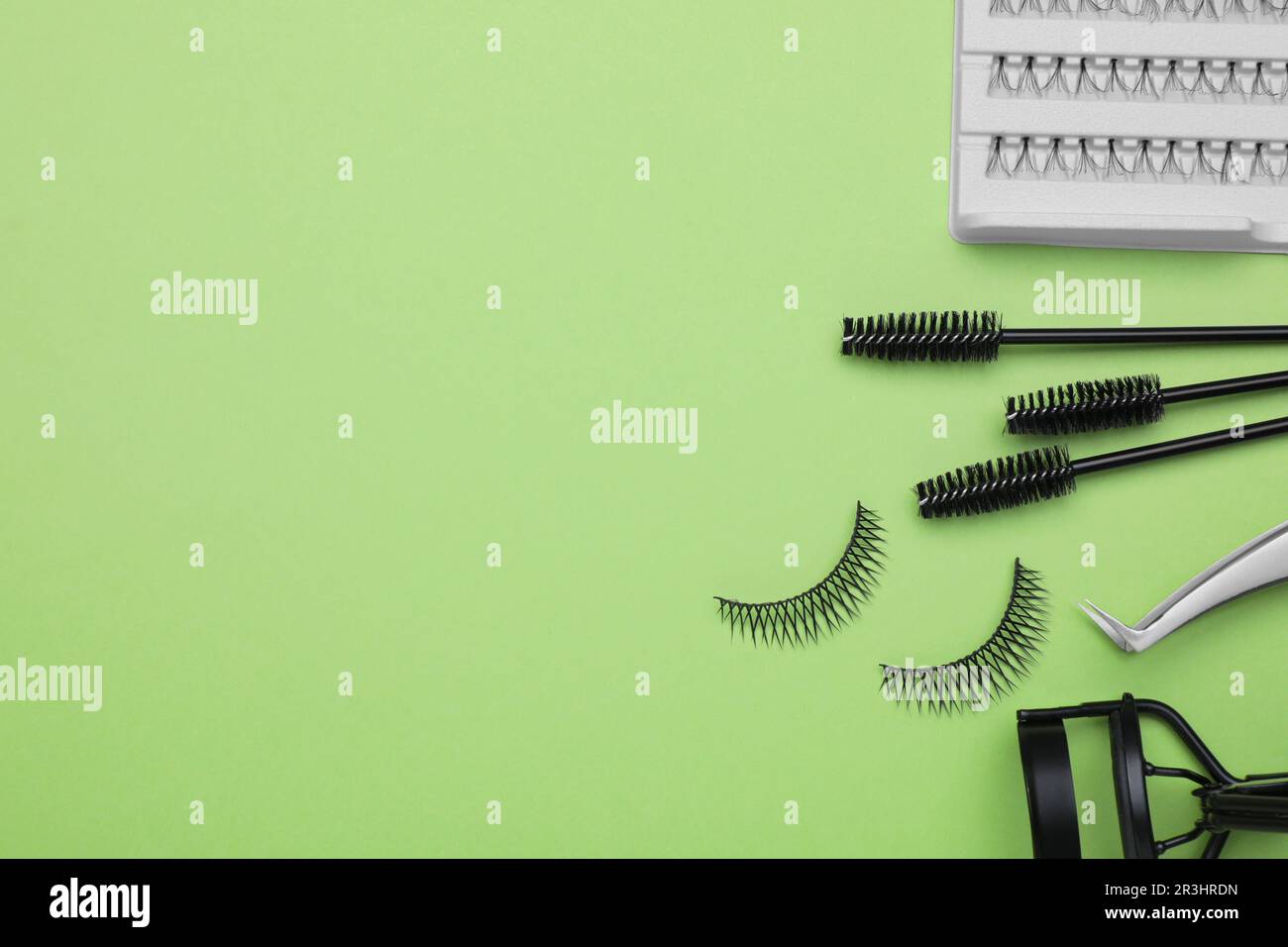 Flat lay composition with fake eyelashes, brushes and tools on green ...