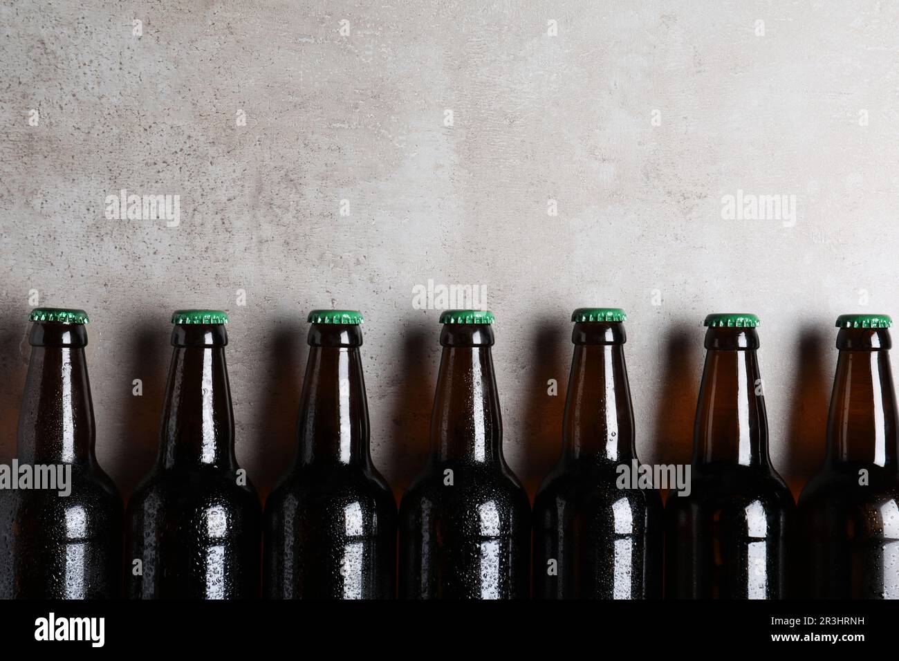 Glass bottles of beer on light grey background, flat lay. Space for ...