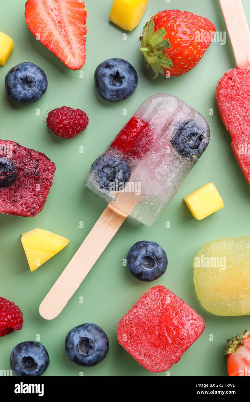 Different tasty ice pops on pale green background, flat lay. Fruit ...