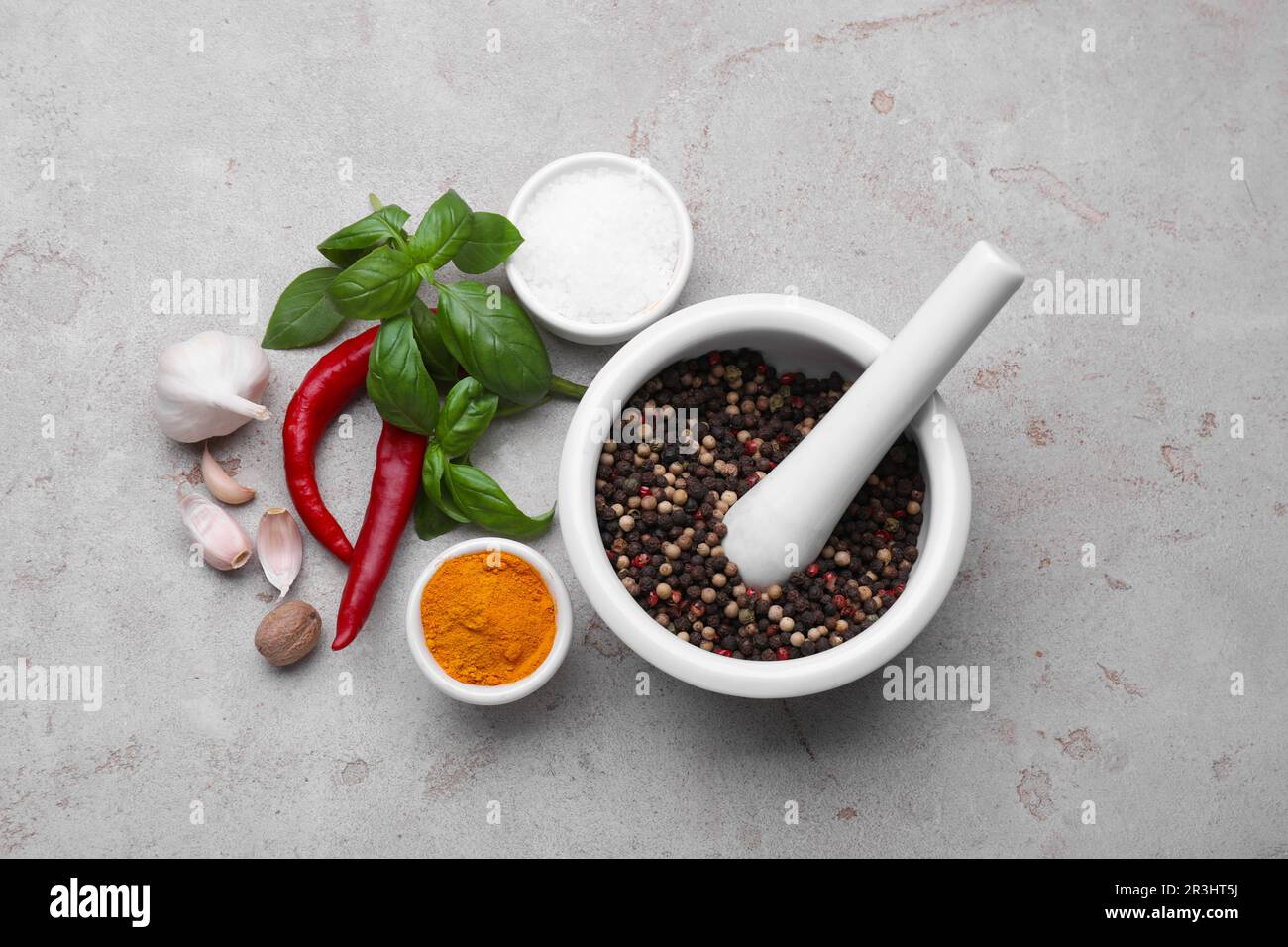 Mortar with pestle and different spices on light grey table, flat lay ...