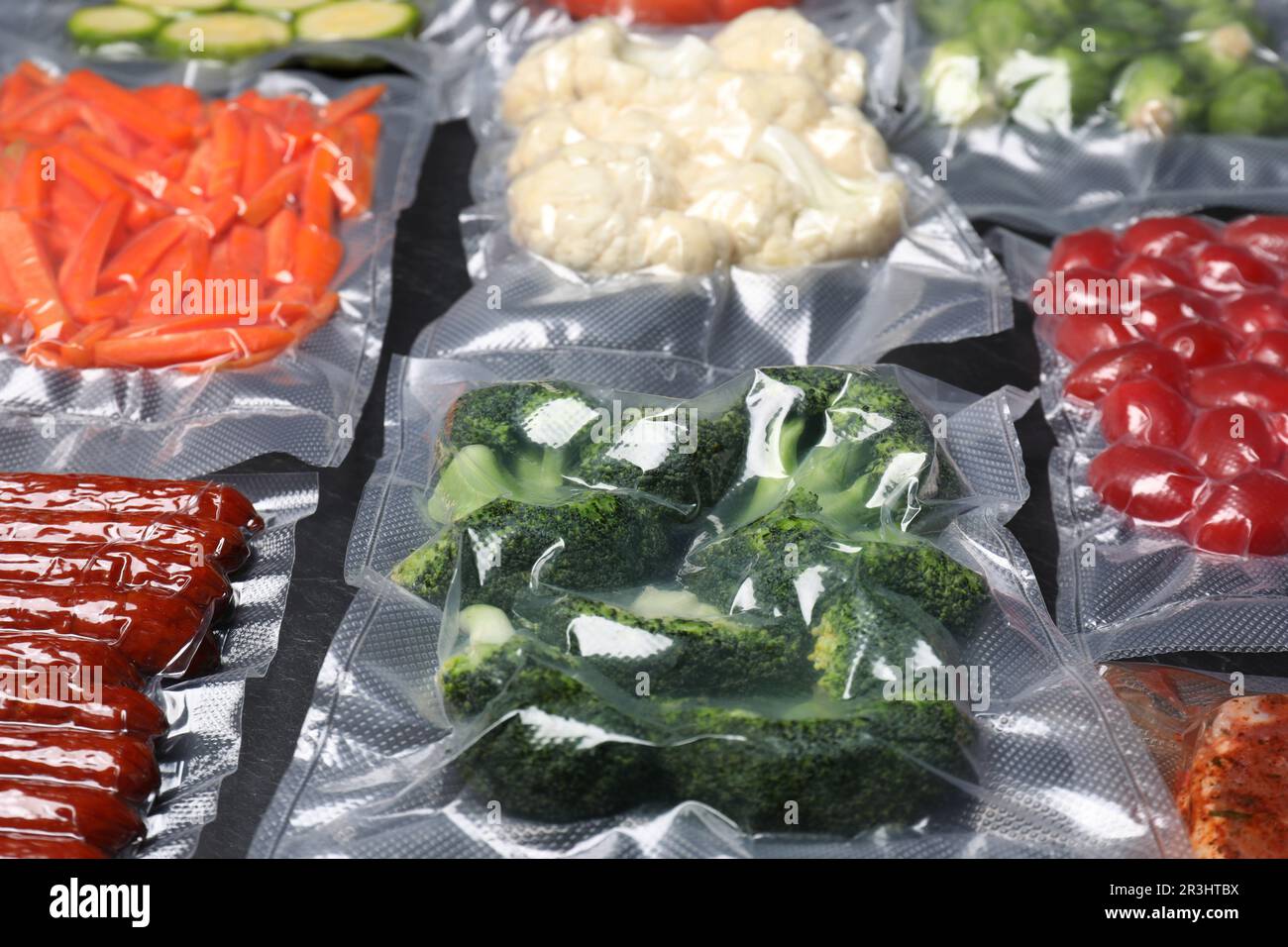 Many different food in vacuum packings on dark grey table, closeup ...