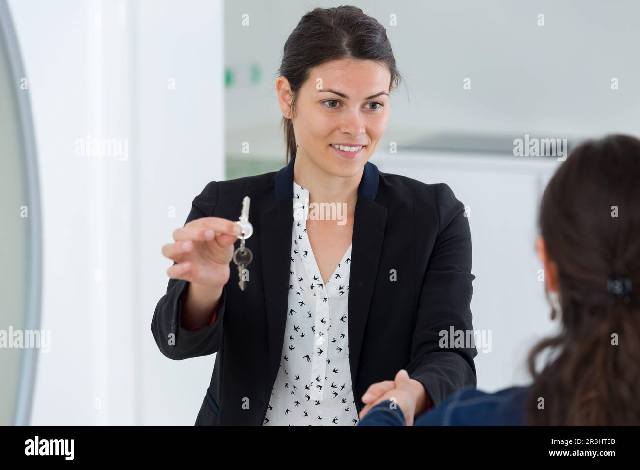 female real estate agent giving keys to customers Stock Photo - Alamy
