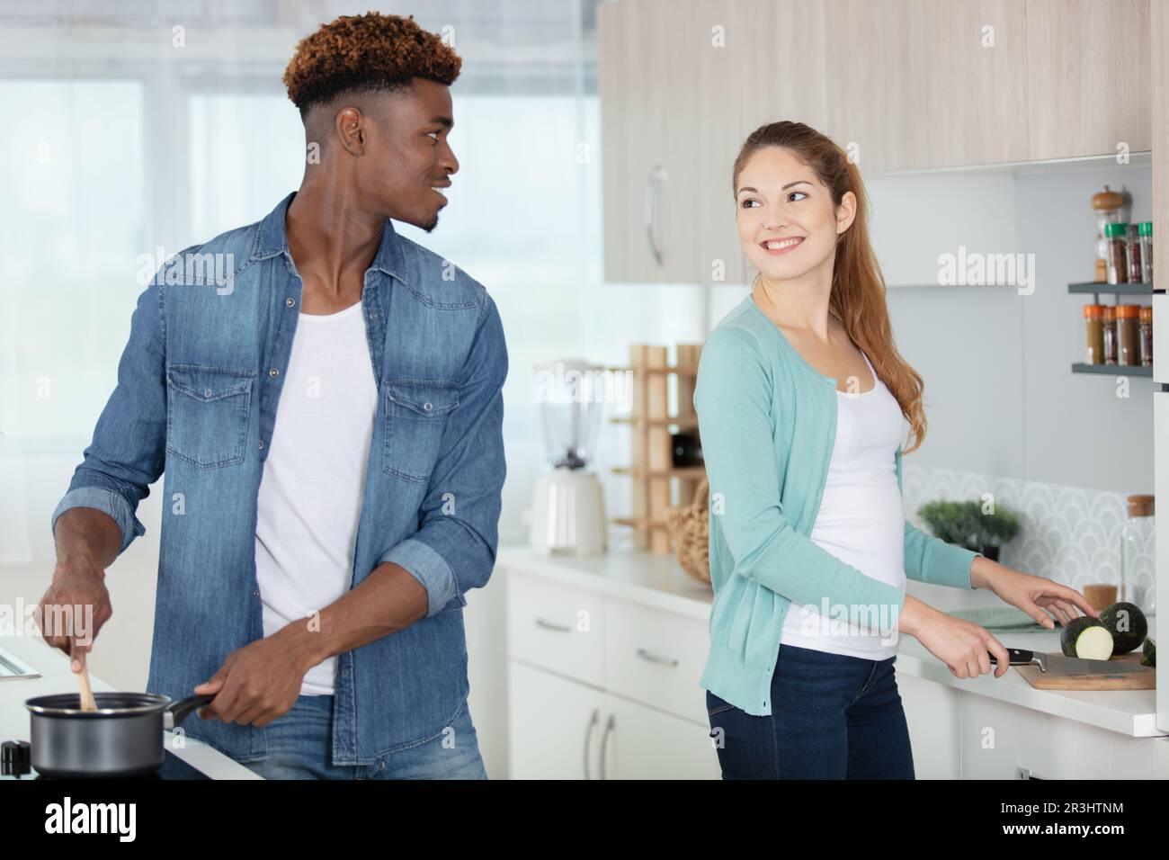 beautiful young couple is smiling while cooking Stock Photo - Alamy