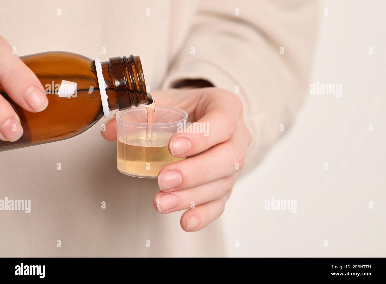 Woman pouring syrup from bottle into measuring cup, closeup. Cold ...