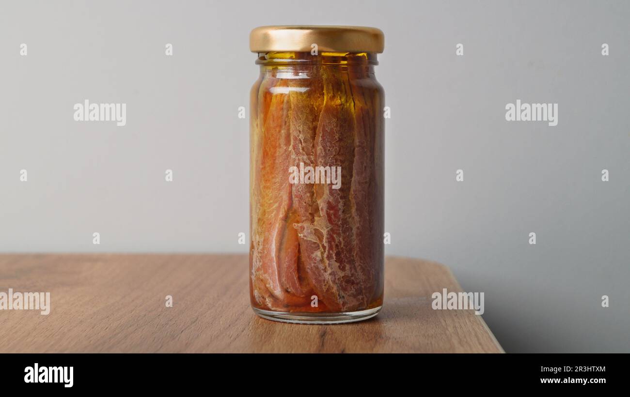 Jar with anchovy fillets in oil on wooden table Stock Photo - Alamy