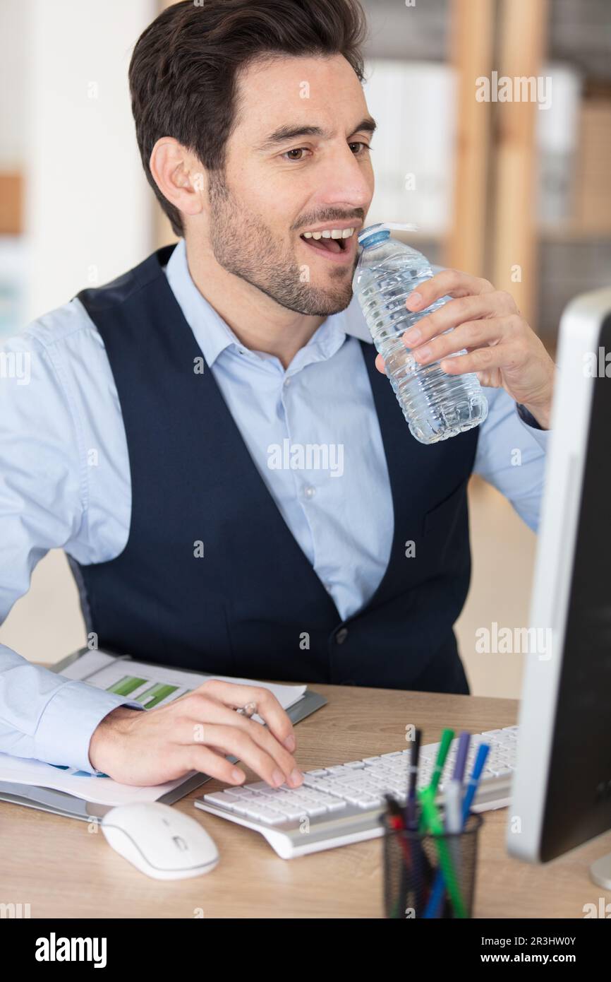 office worker drinking water in front of desktop computer Stock Photo ...