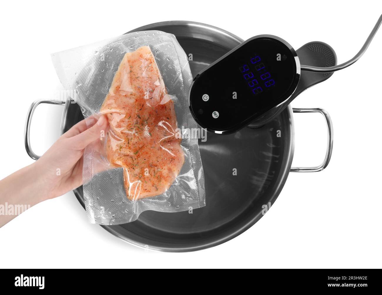 Woman putting vacuum packed meat into pot with sous vide cooker on ...