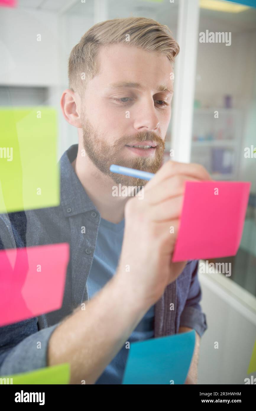 man writing at sticky notes on window Stock Photo - Alamy