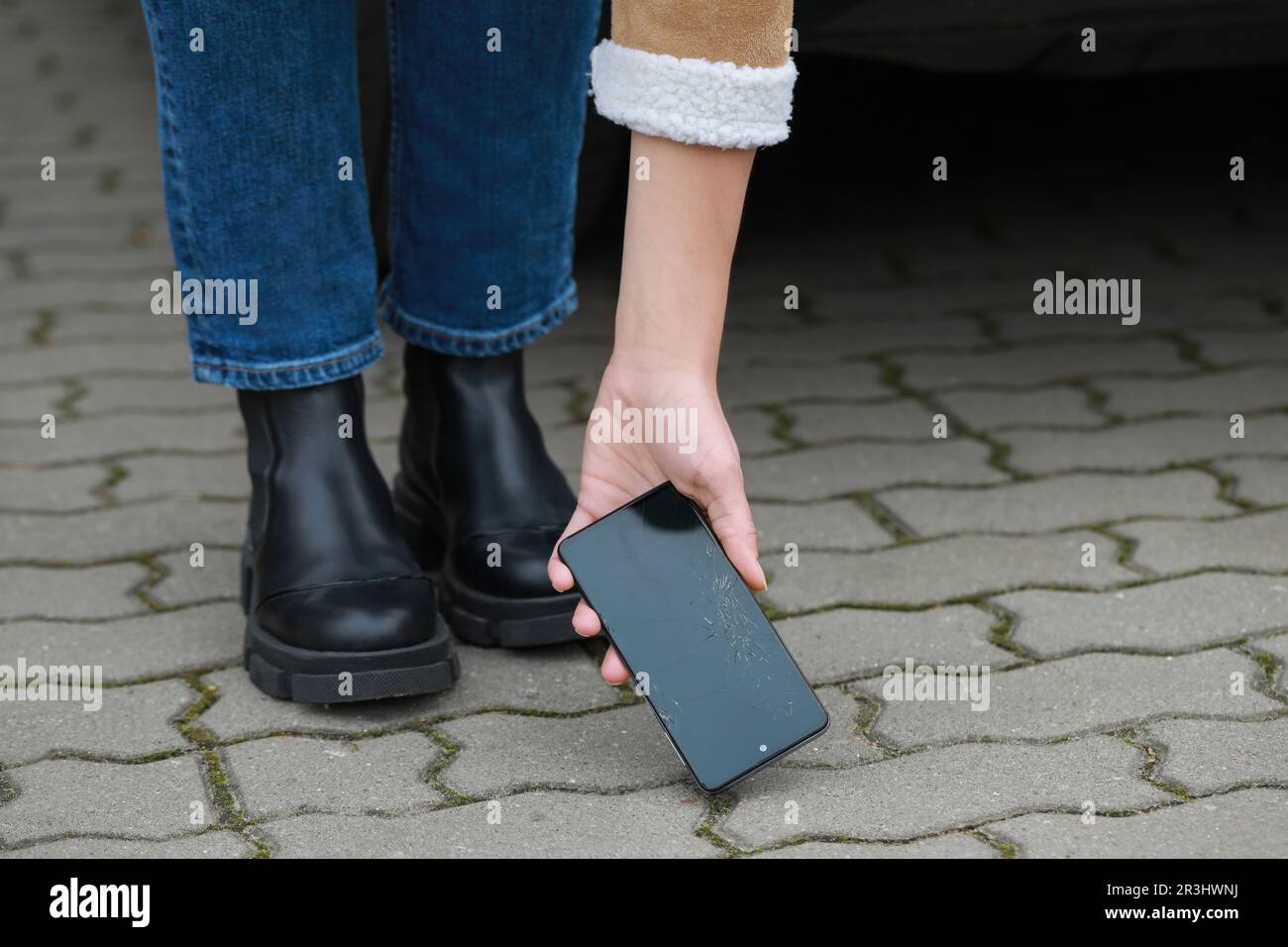 Woman taking dropped smartphone from pavement, closeup. Device ...