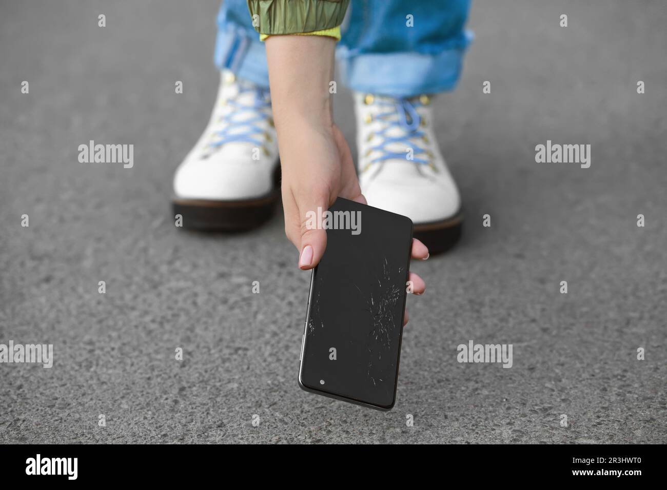 Woman taking dropped smartphone from asphalt, closeup. Device repairing ...