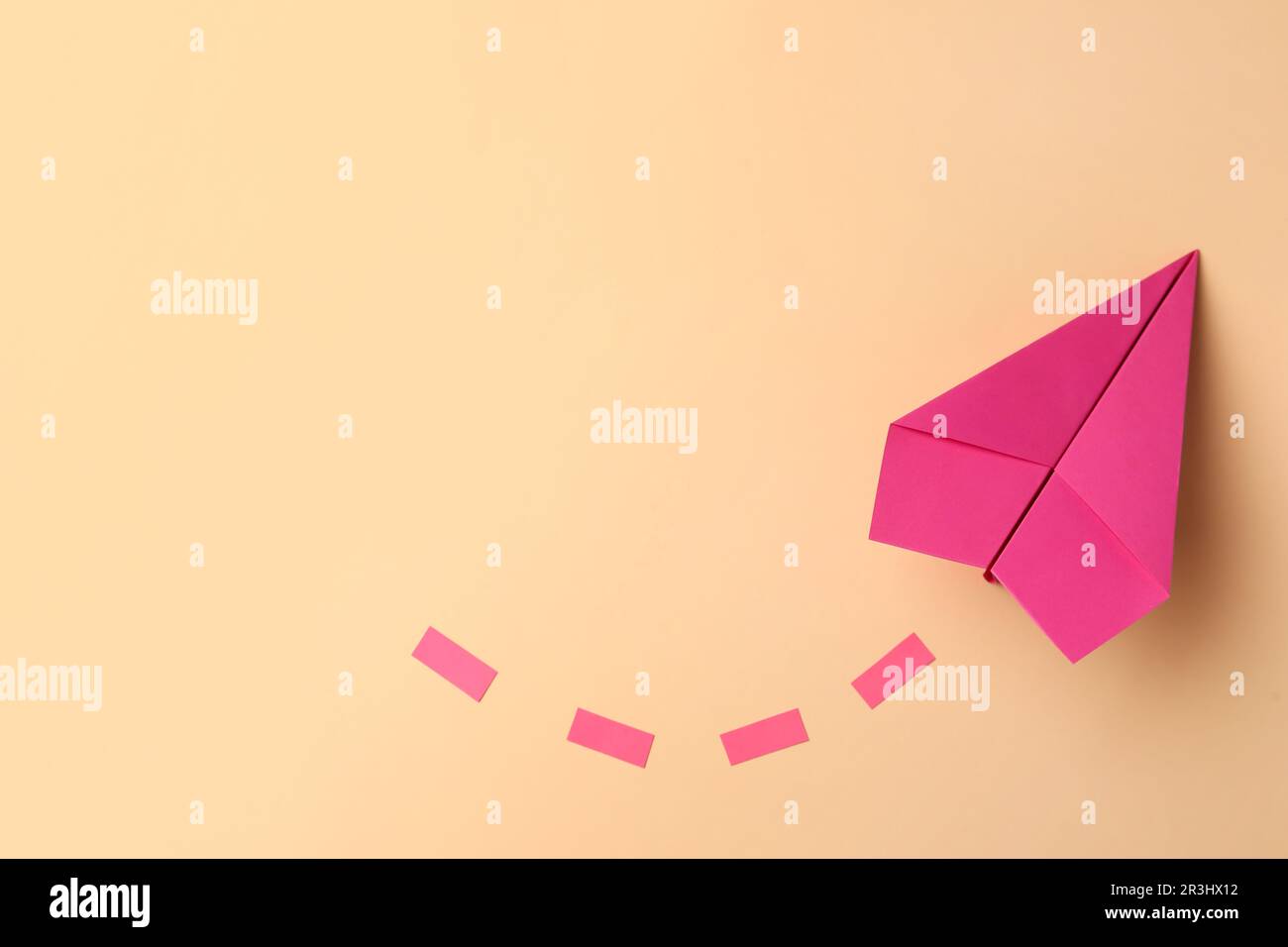Handmade pink paper plane with dotted lines on beige background, top ...