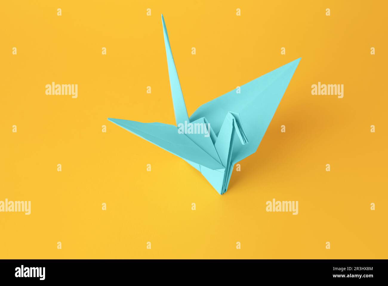 Origami art. Beautiful light blue paper crane on orange background ...