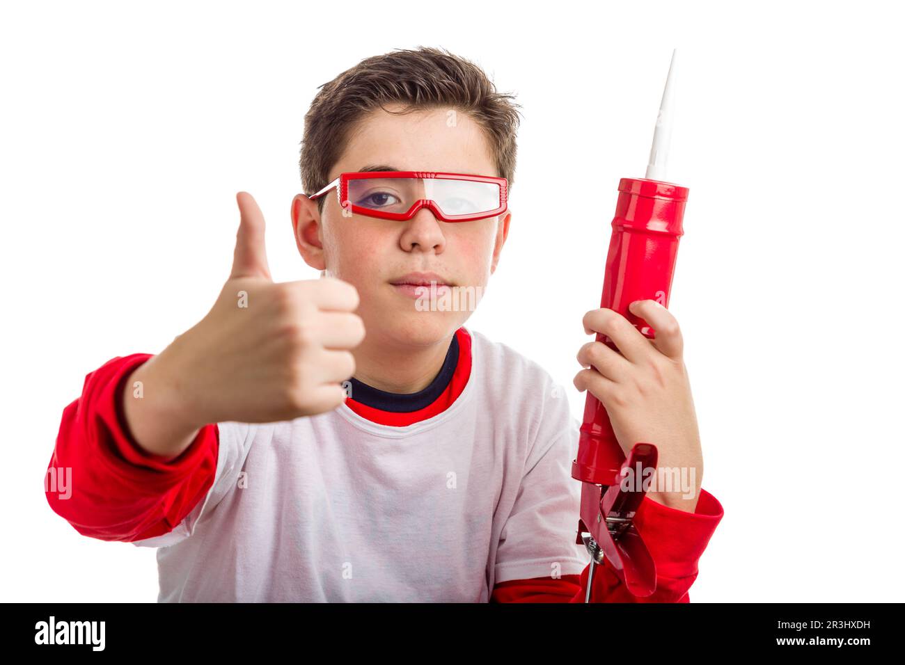 Boy wearing red goggles and holding a caulking gun makes success sign ...