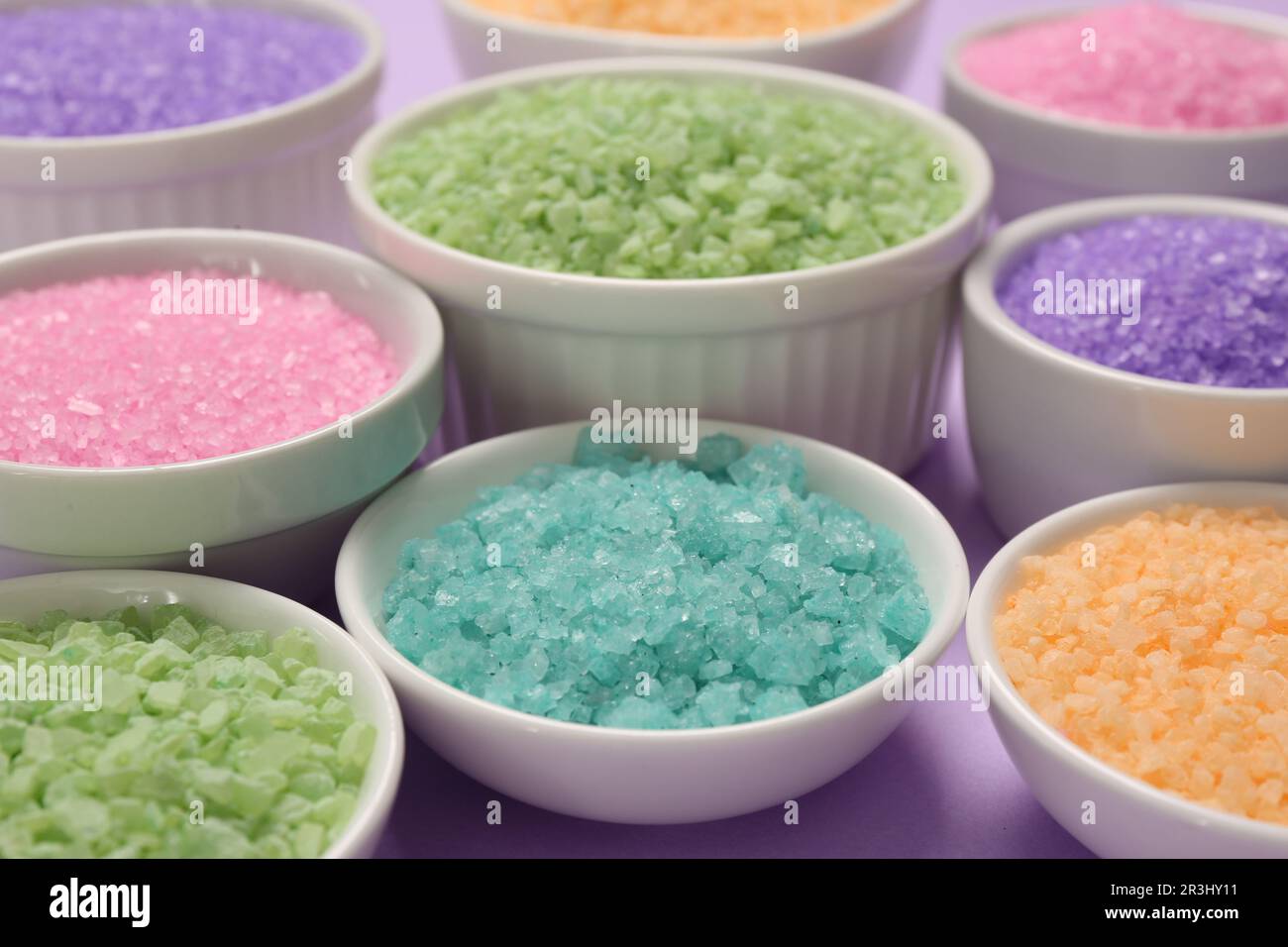 Different types of aromatic sea salt on purple background, closeup ...