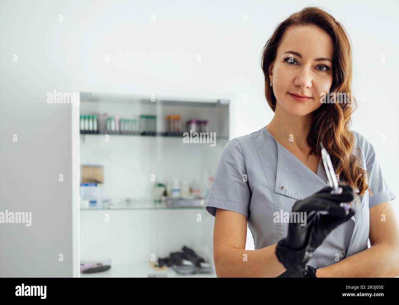 Close up of woman in medical gloves holding syringe with clear liquid ...
