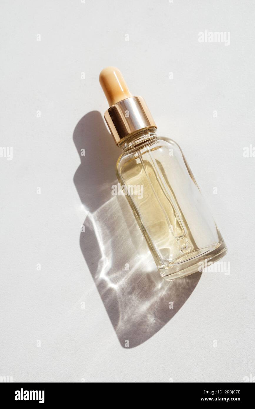 Serum with collagen and peptides in transparent glass bottle on light ...