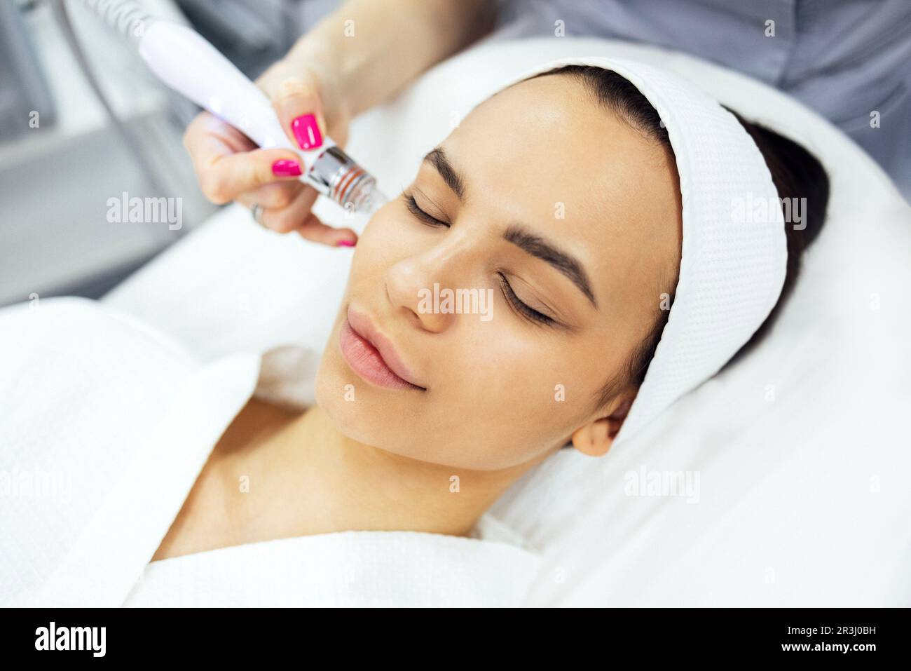Brunette young woman undergoes a procedure of vitamin peeling in beauty ...