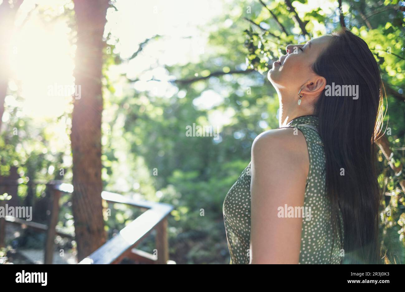 Charming young woman with long hair stands on path in forest and looks ...
