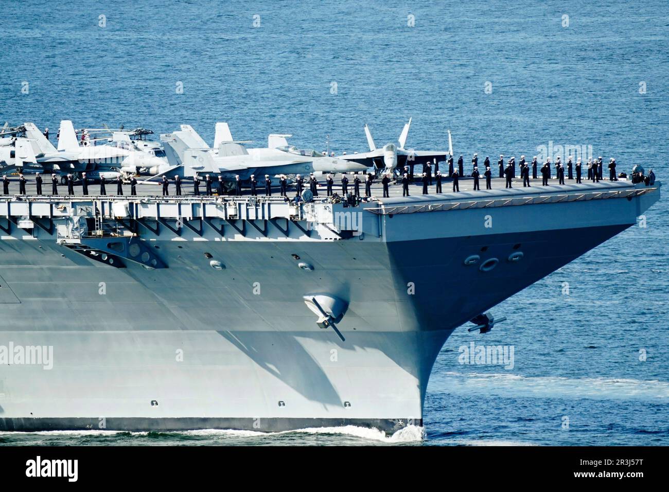 The crew of the aircraft carrier USS Gerald R. Ford stands on the ...