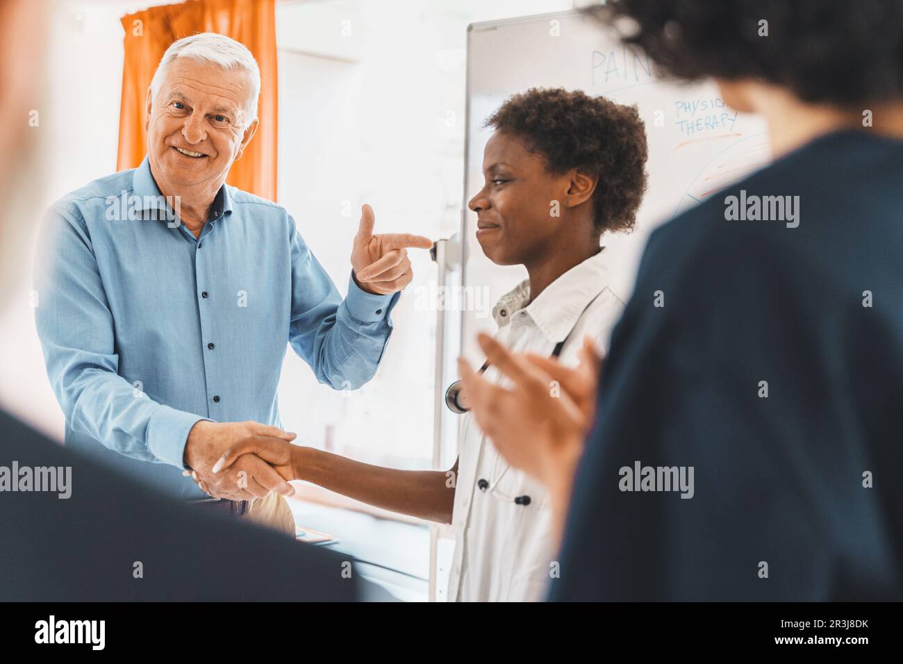 Senior medical professor congratulating an African female student ...