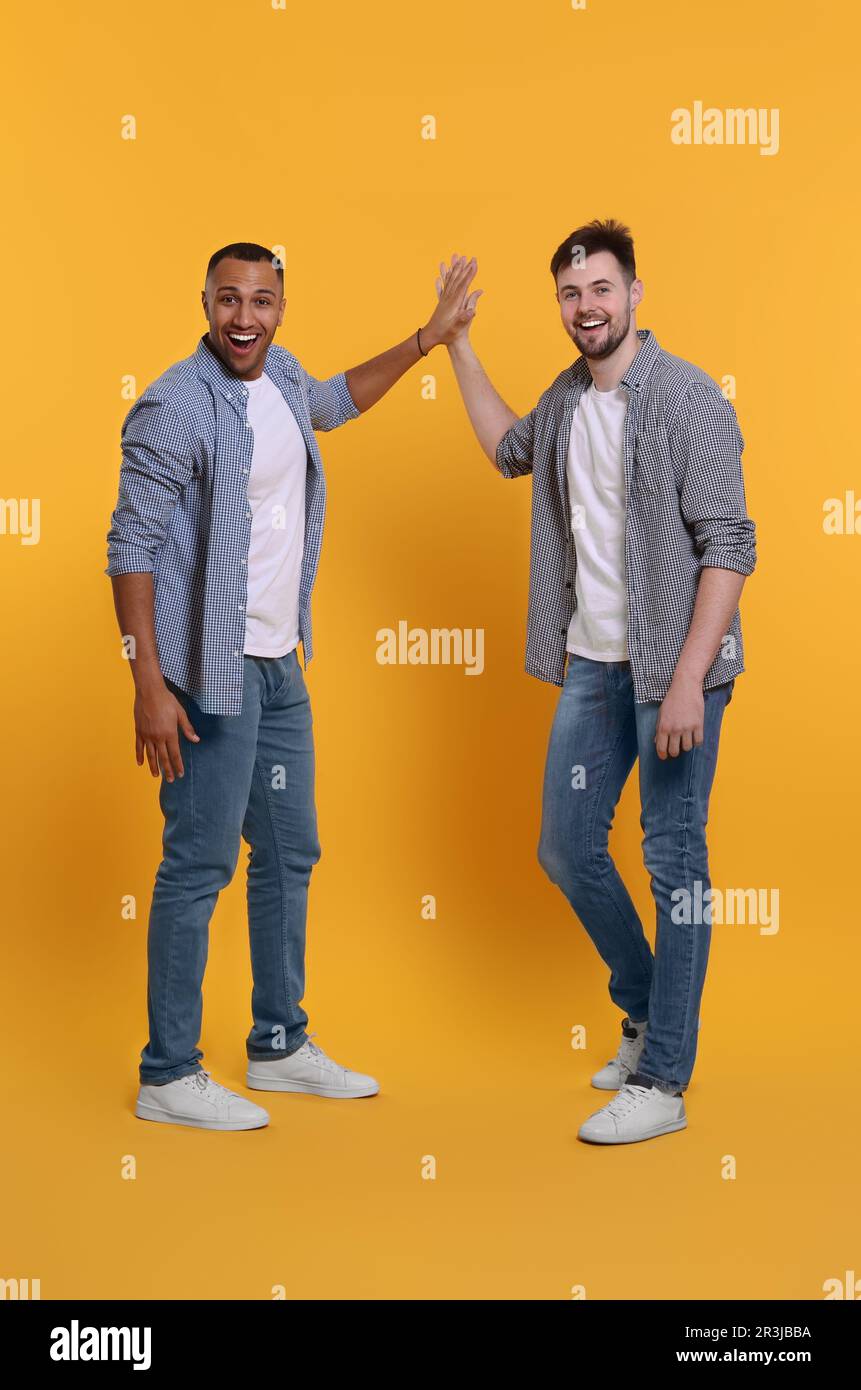 Men giving high five on yellow background Stock Photo - Alamy