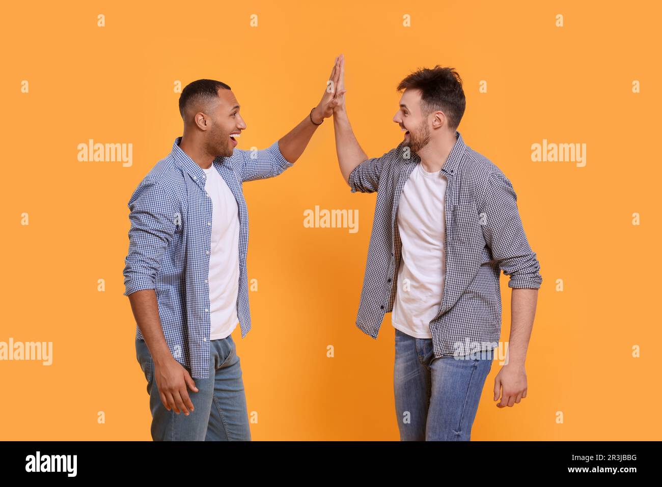 Men giving high five on yellow background Stock Photo - Alamy