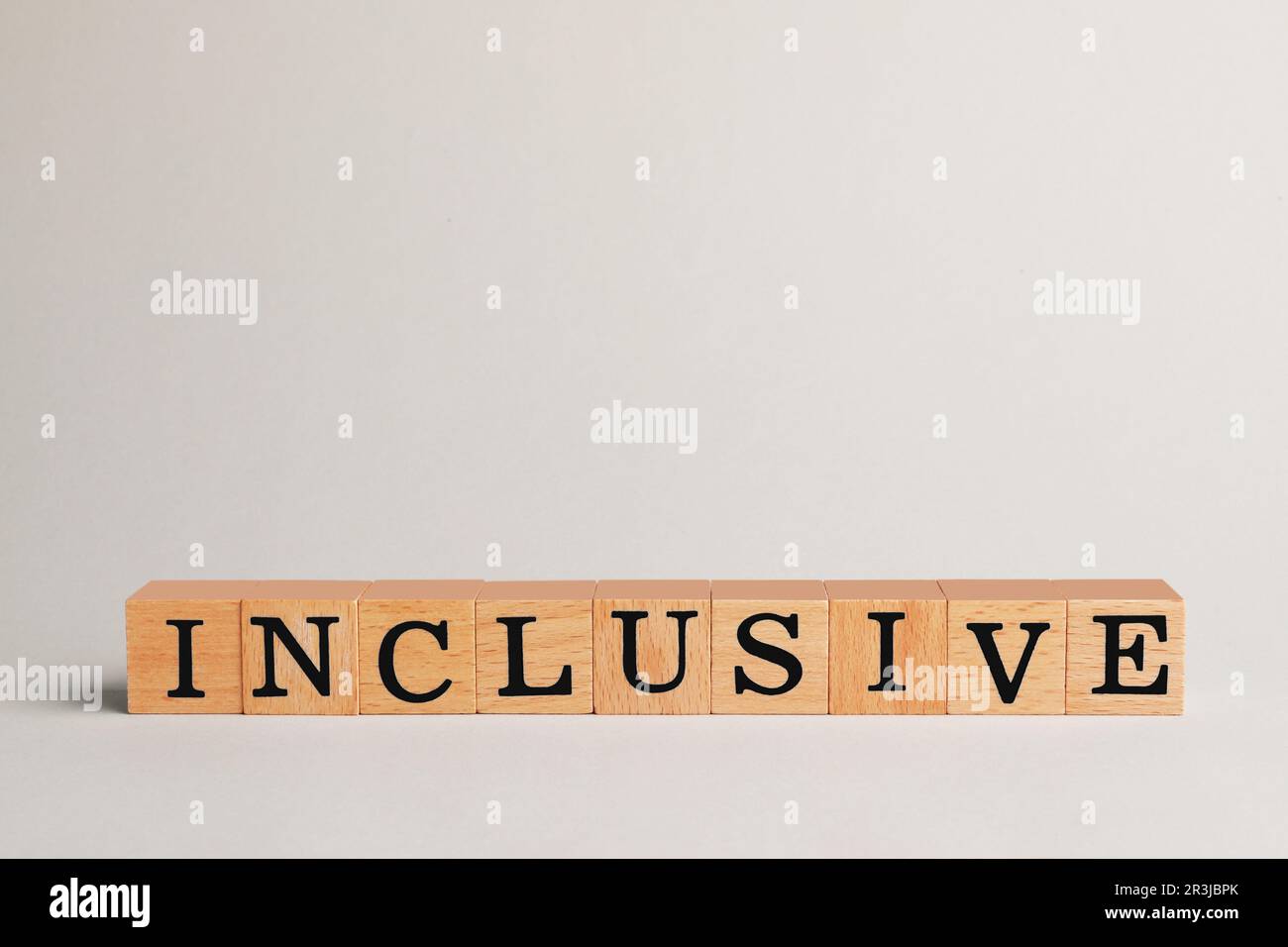Wooden cubes with word Inclusive on beige background. Space for text ...