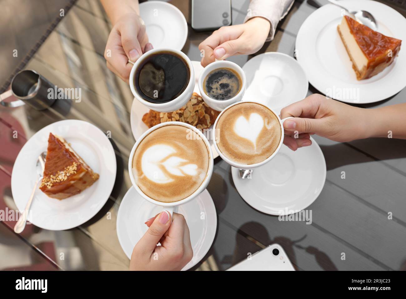 Friends drinking coffee at wooden table in outdoor cafe, top view Stock ...