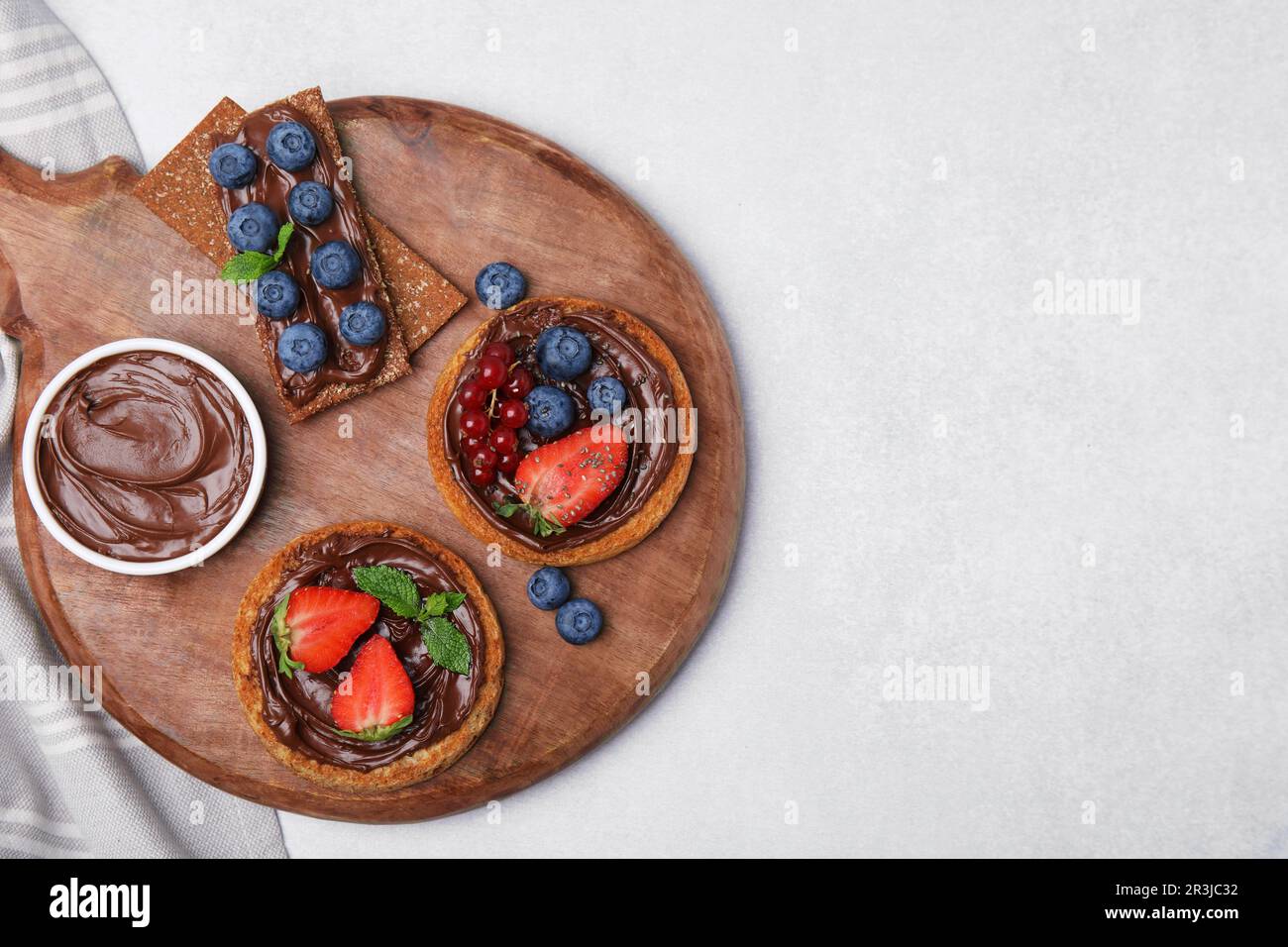 Fresh rye crispbreads and rusks with different toppings on light grey ...