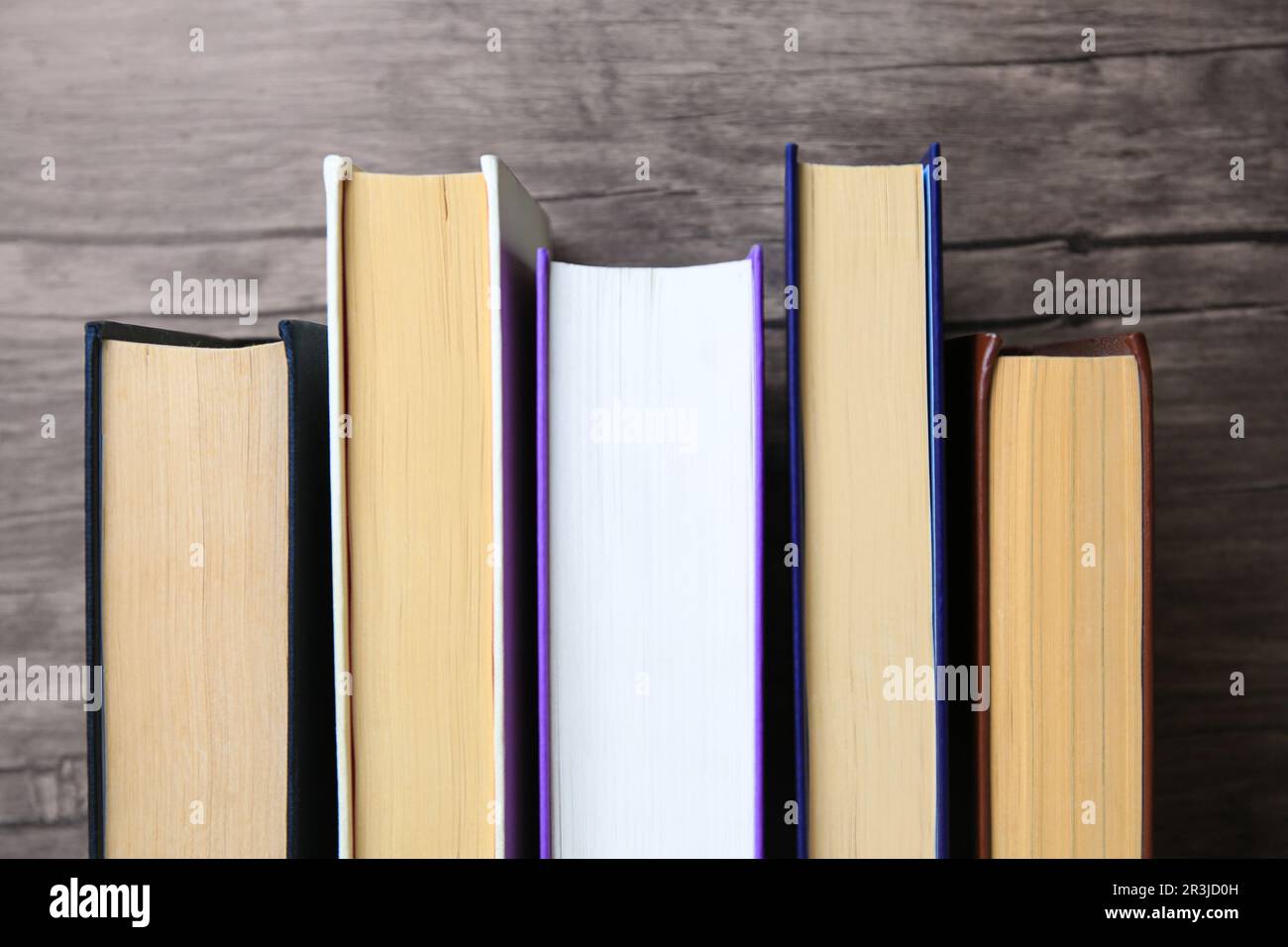 Collection of different books near wooden wall, closeup Stock Photo - Alamy