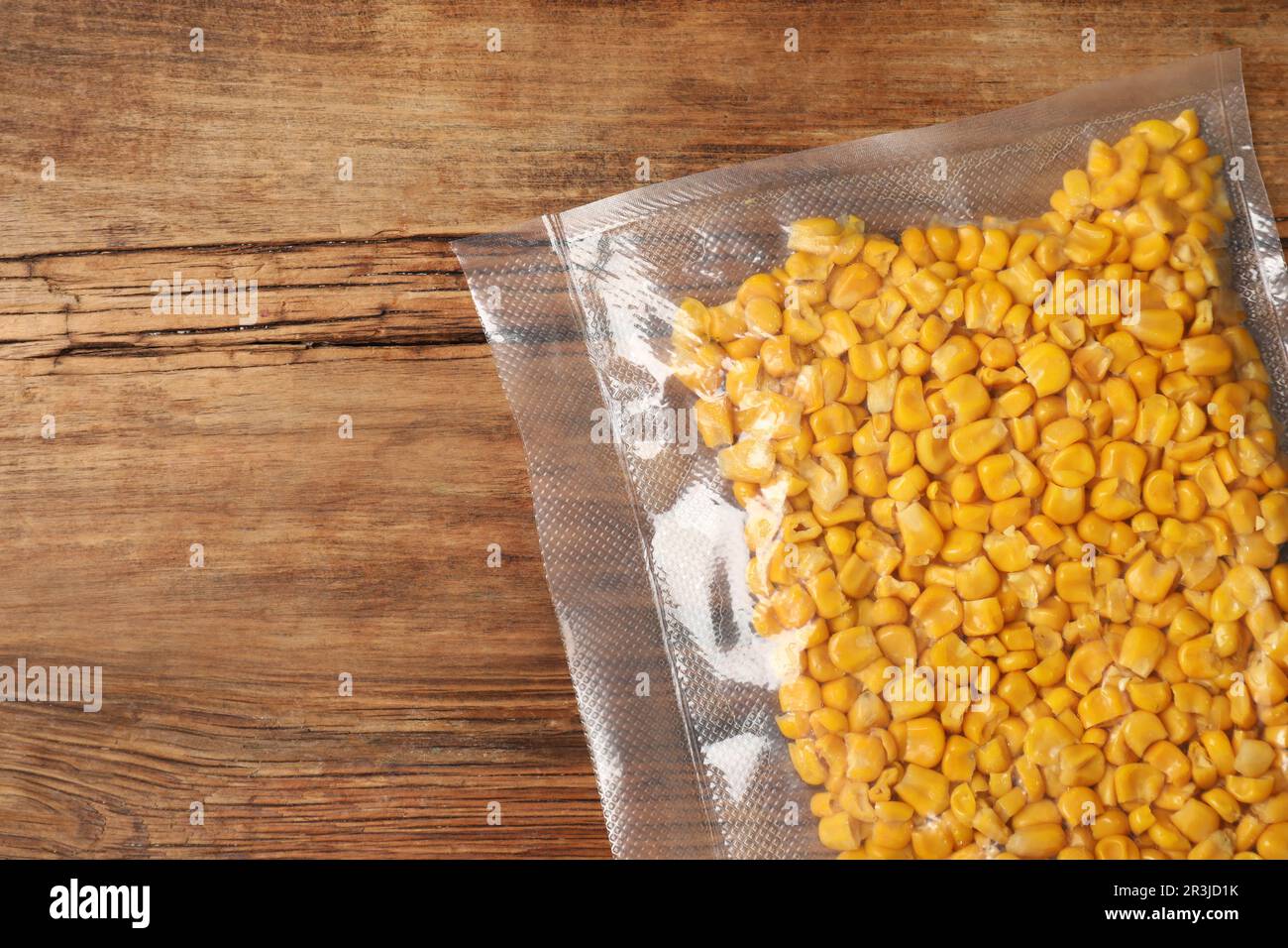 Vacuum pack of corn on wooden table, top view. Space for text Stock ...