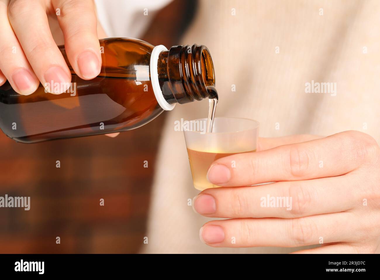 Woman pouring syrup from bottle into measuring cup, closeup. Cold ...