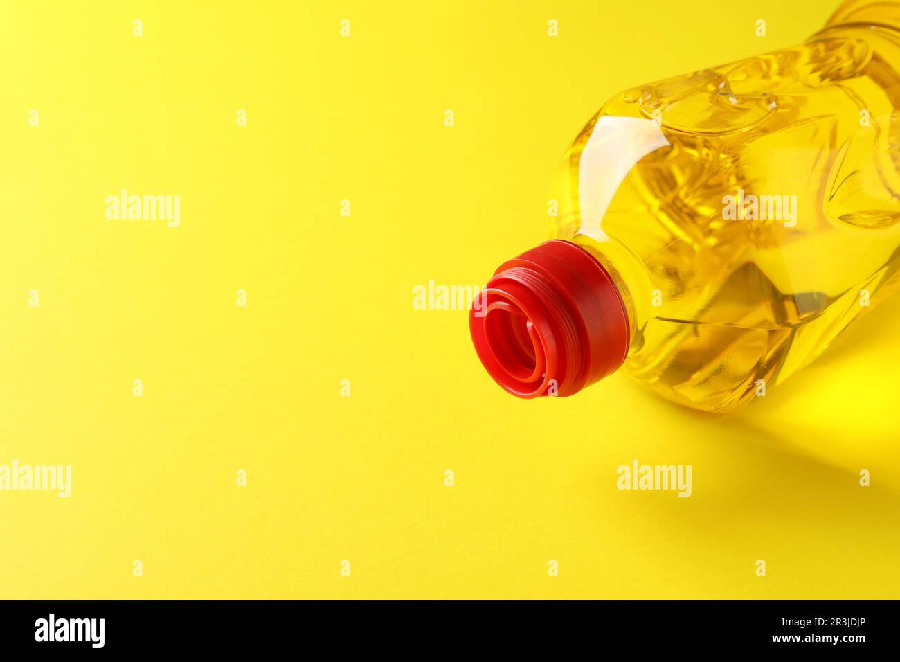 Plastic bottle of cooking oil on yellow background. Space for text ...