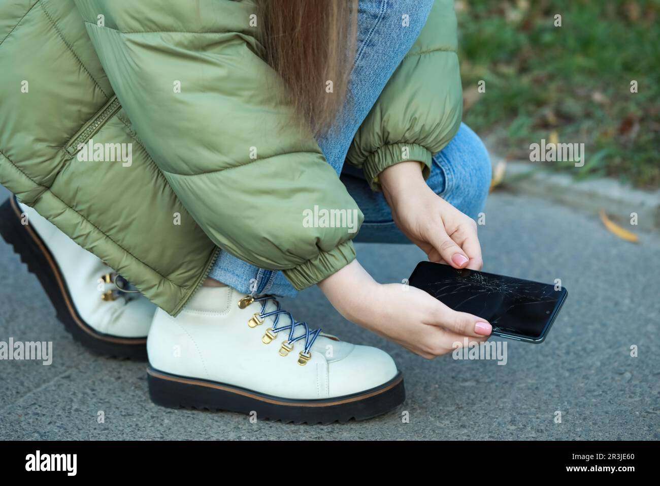 Woman taking dropped smartphone from asphalt outdoors, closeup. Device ...