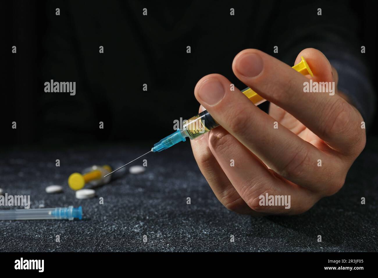Drug addiction. Man with syringe on black textured table, closeup and ...