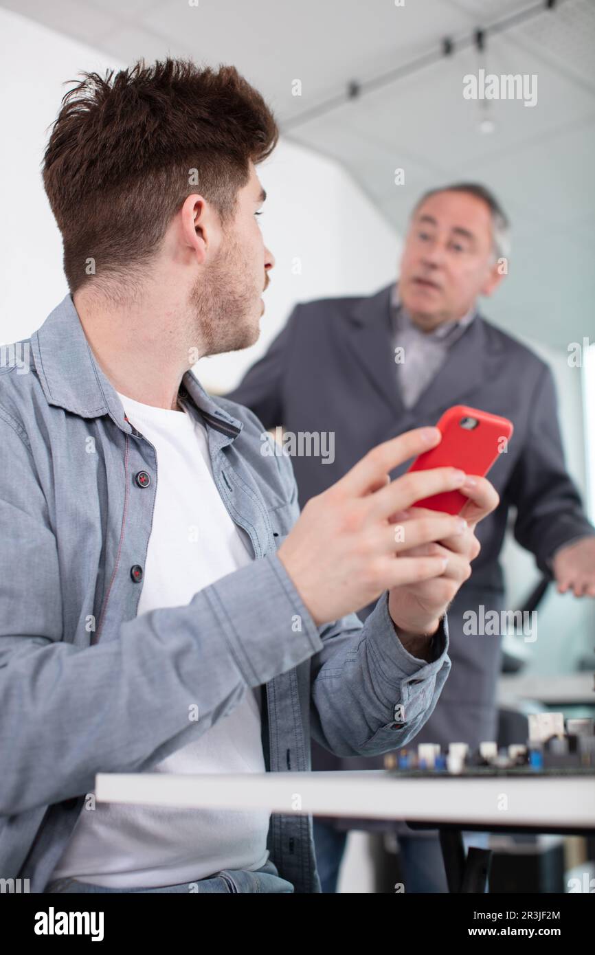upset senior craftsman telling off apprentice Stock Photo - Alamy