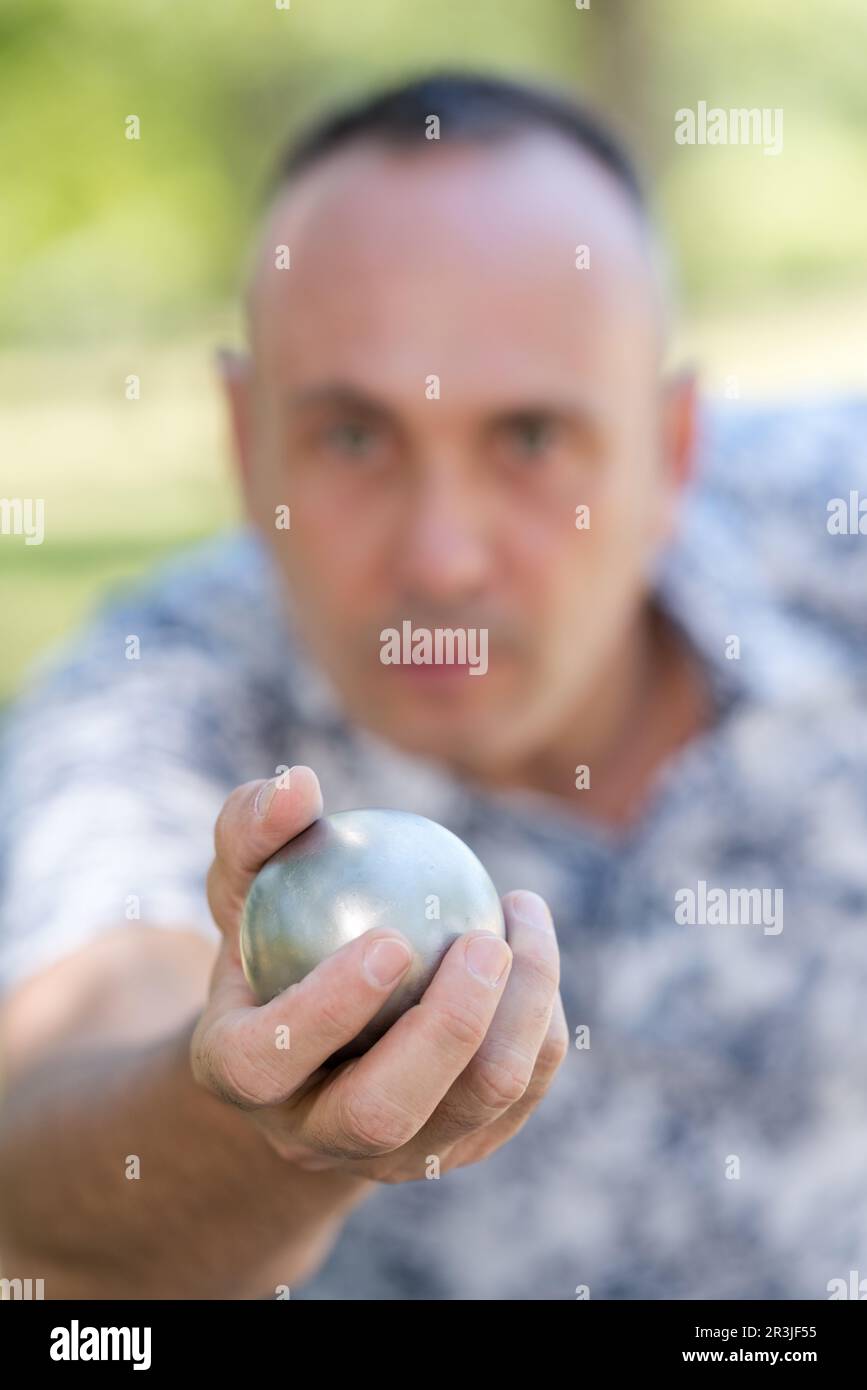 man with petanque ball in his hand taking aim Stock Photo - Alamy