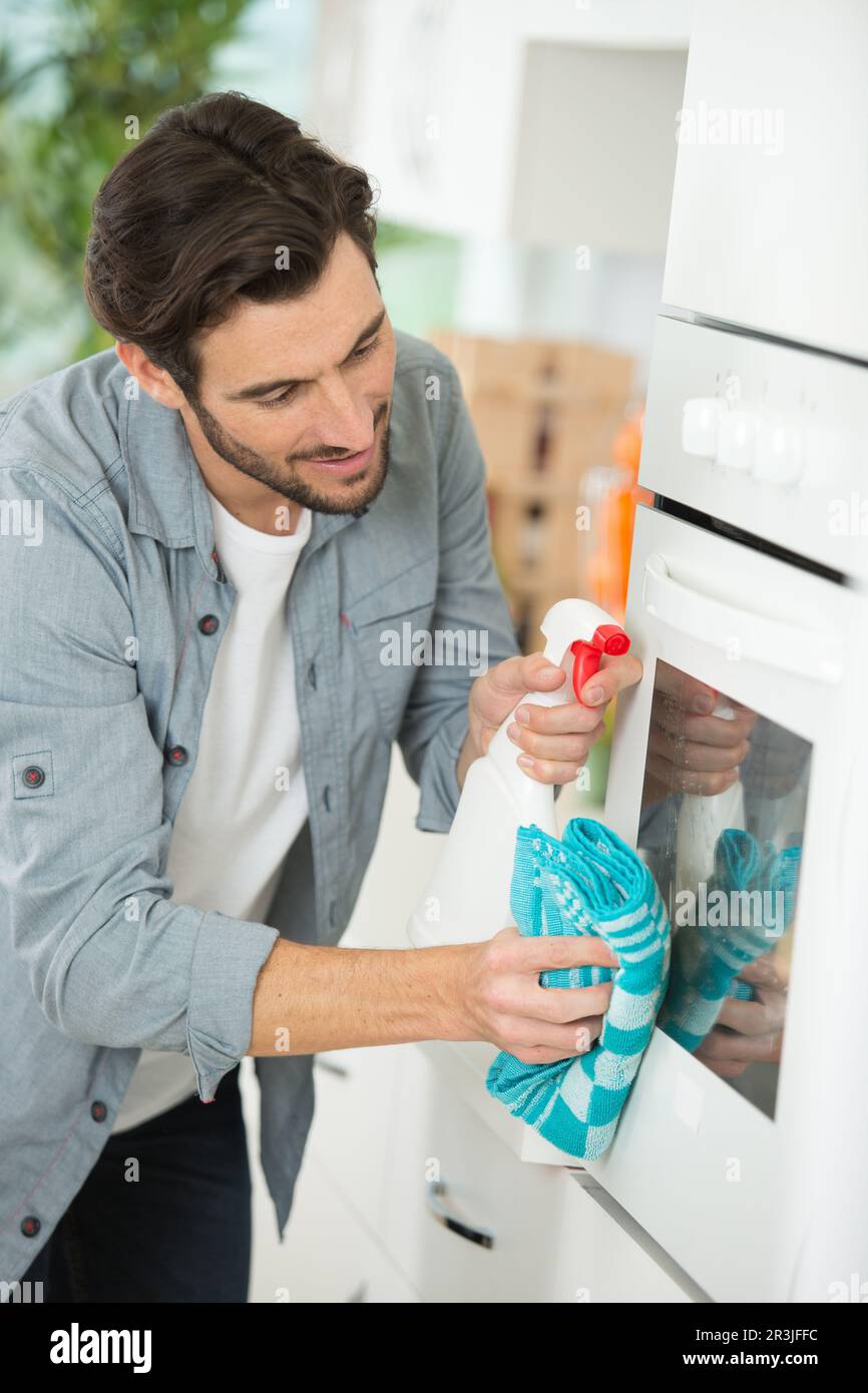 man cleaning oven using detergent spray Stock Photo - Alamy