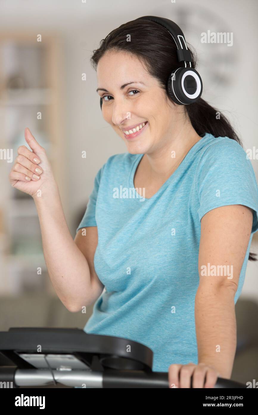 woman listening to music while using exercise machine Stock Photo - Alamy