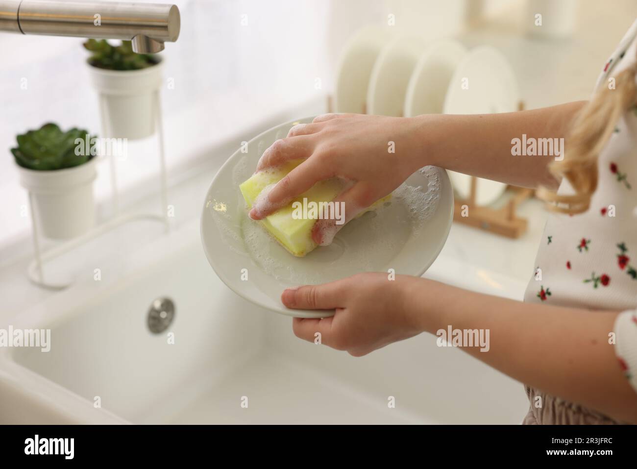 Little girl washing plate above sink, closeup Stock Photo - Alamy