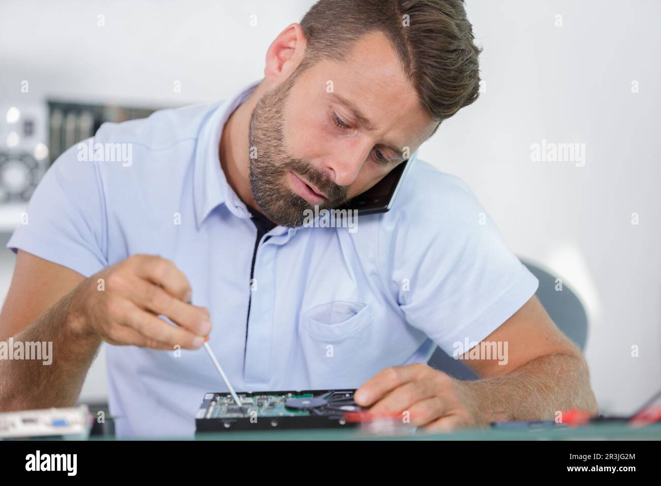 man on the phone while fixing a pc Stock Photo - Alamy