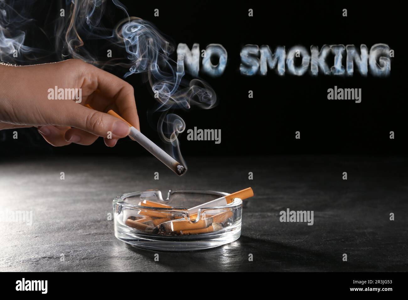 No Smoking, phrase of smoke. Woman holding smoldering cigarette over ...