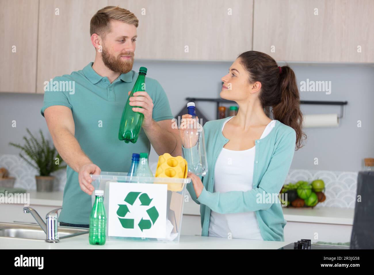 a young couple recycling plastic in their kitchen Stock Photo - Alamy
