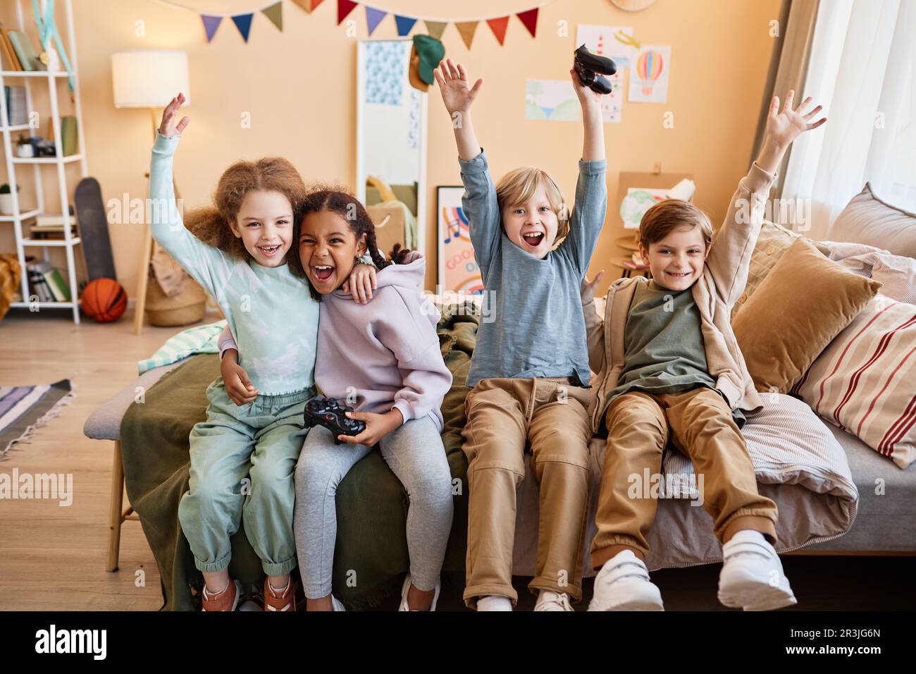 Diverse group of excited little children playing video games together ...