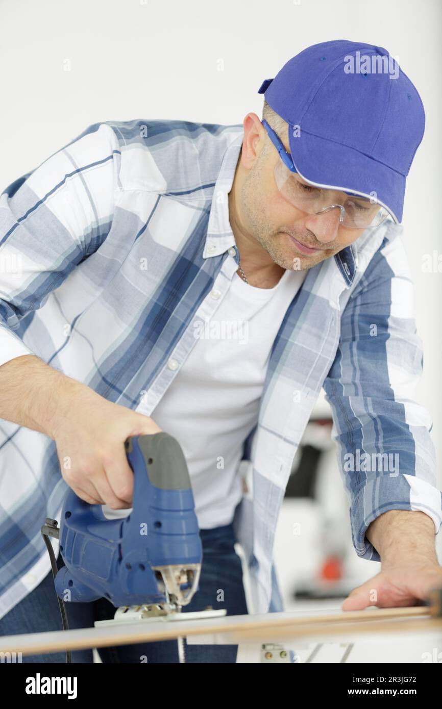 male builder cutting a wood board Stock Photo - Alamy